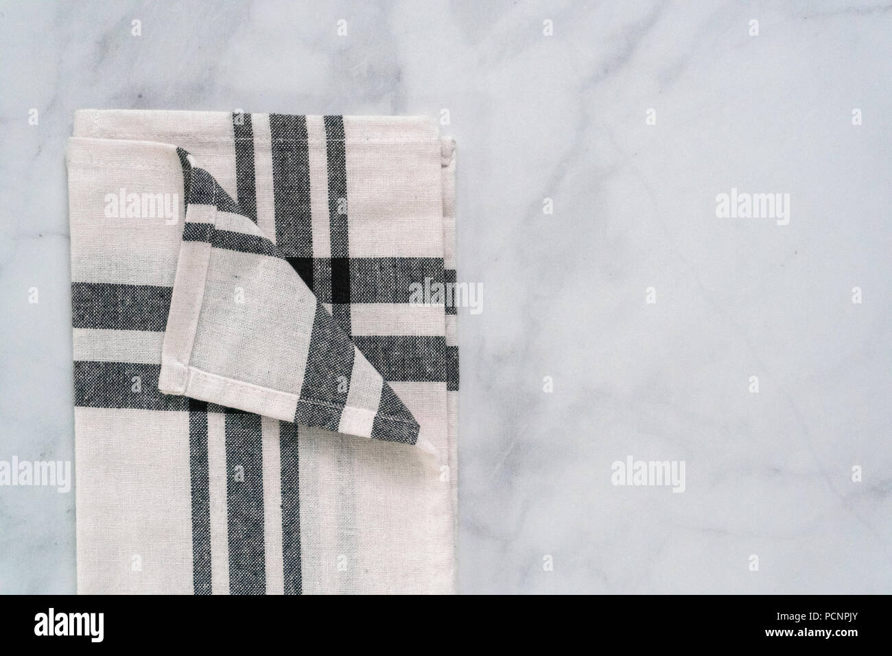 New kitchen towels with simple black pattern folded on marble counter ...