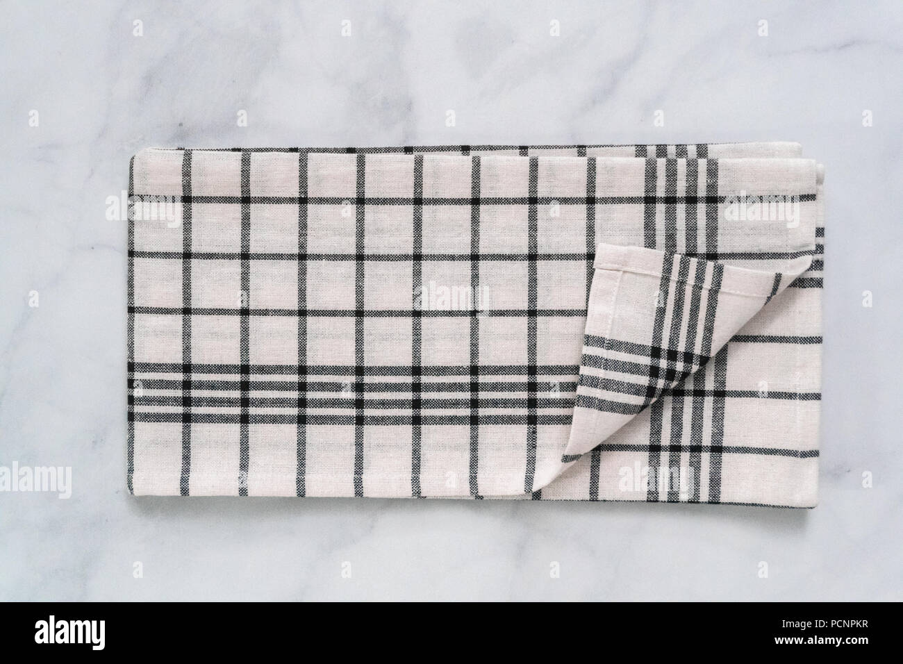 New kitchen towels with simple black pattern folded on marble counter ...