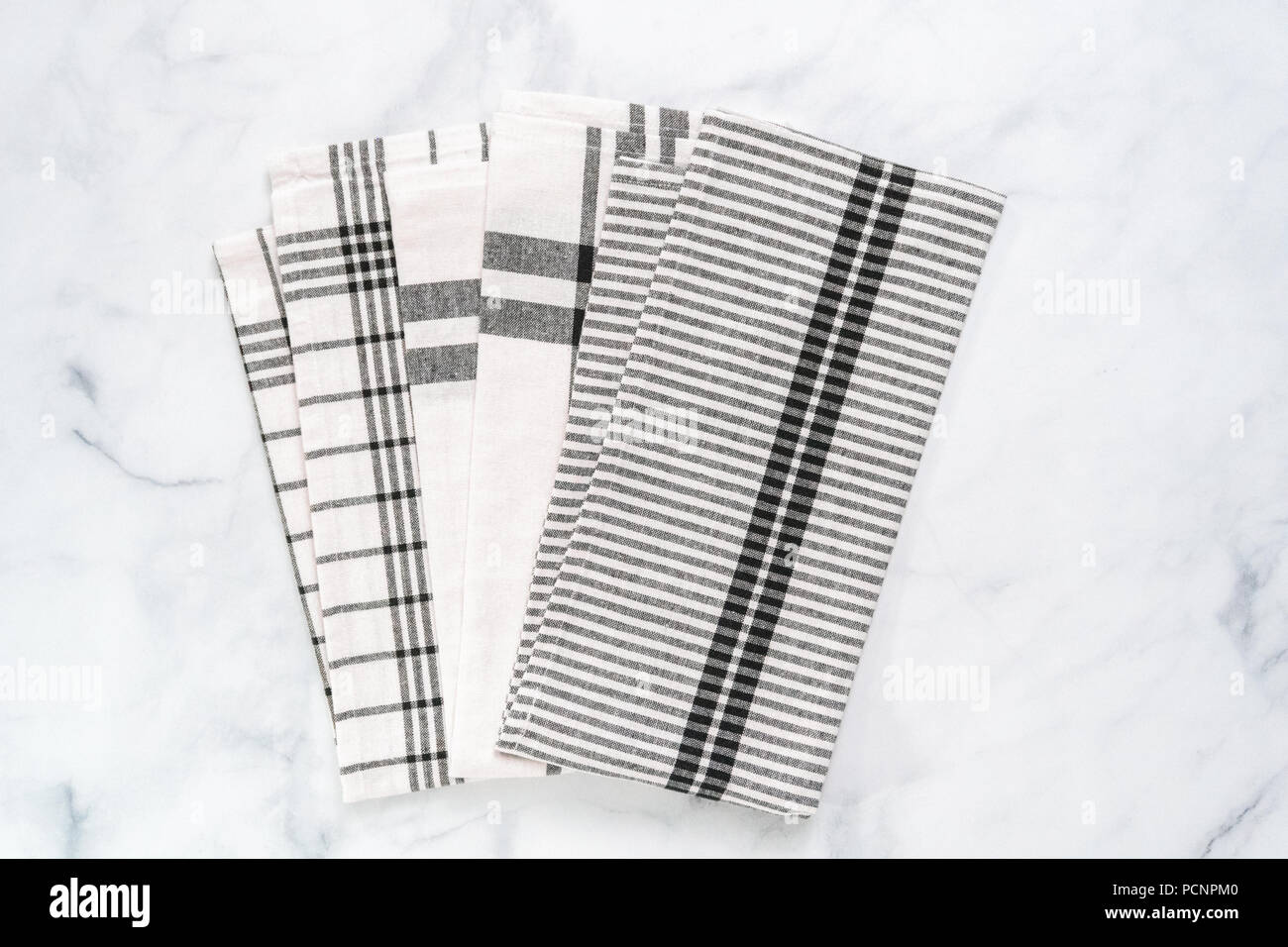New kitchen towels with simple black pattern folded on marble counter ...