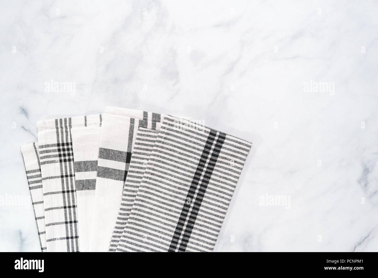 New kitchen towels with simple black pattern folded on marble counter ...