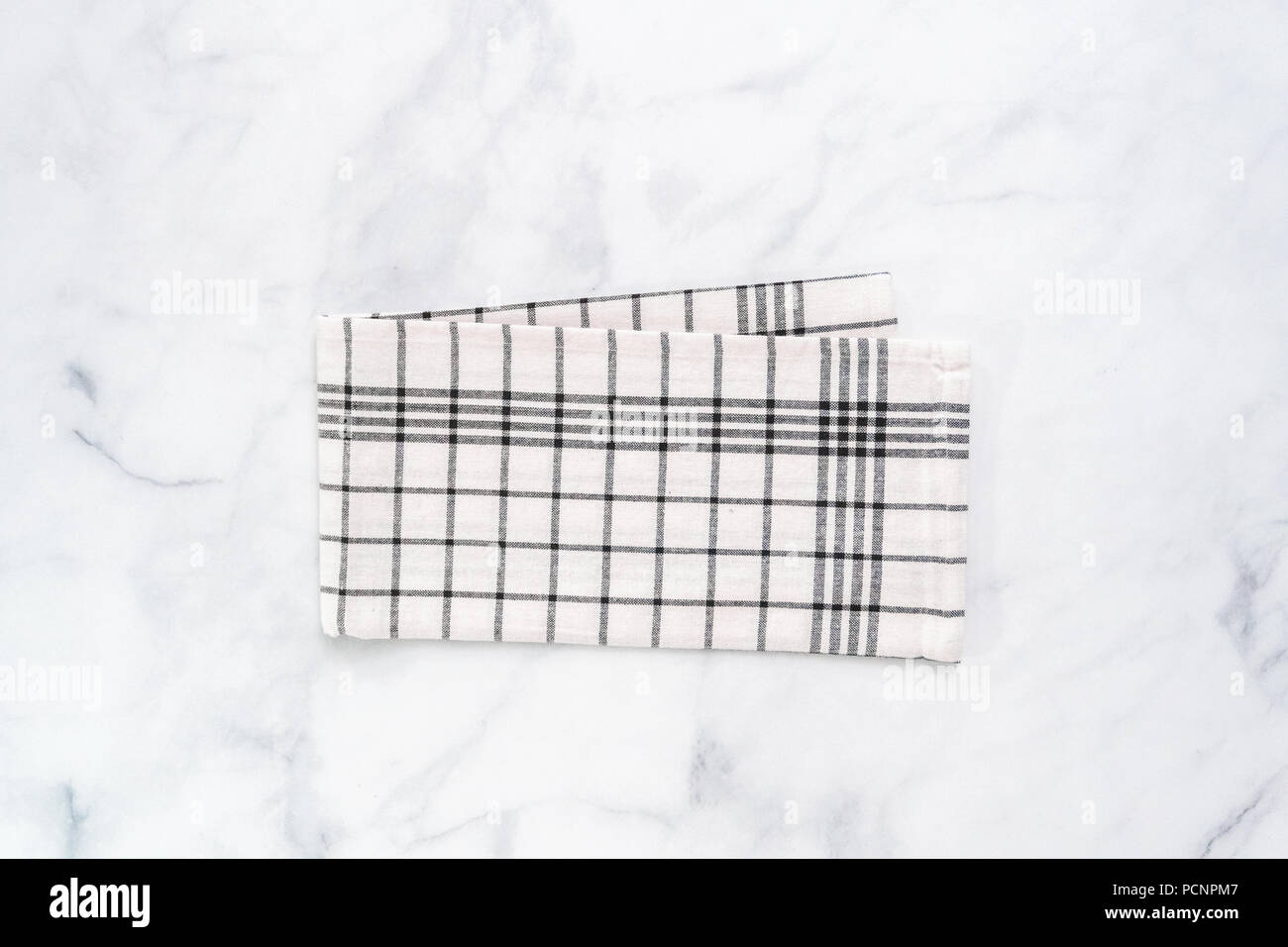 New kitchen towels with simple black pattern folded on marble counter ...