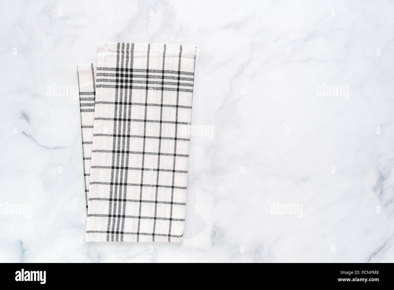 New kitchen towels with simple black pattern folded on marble counter ...