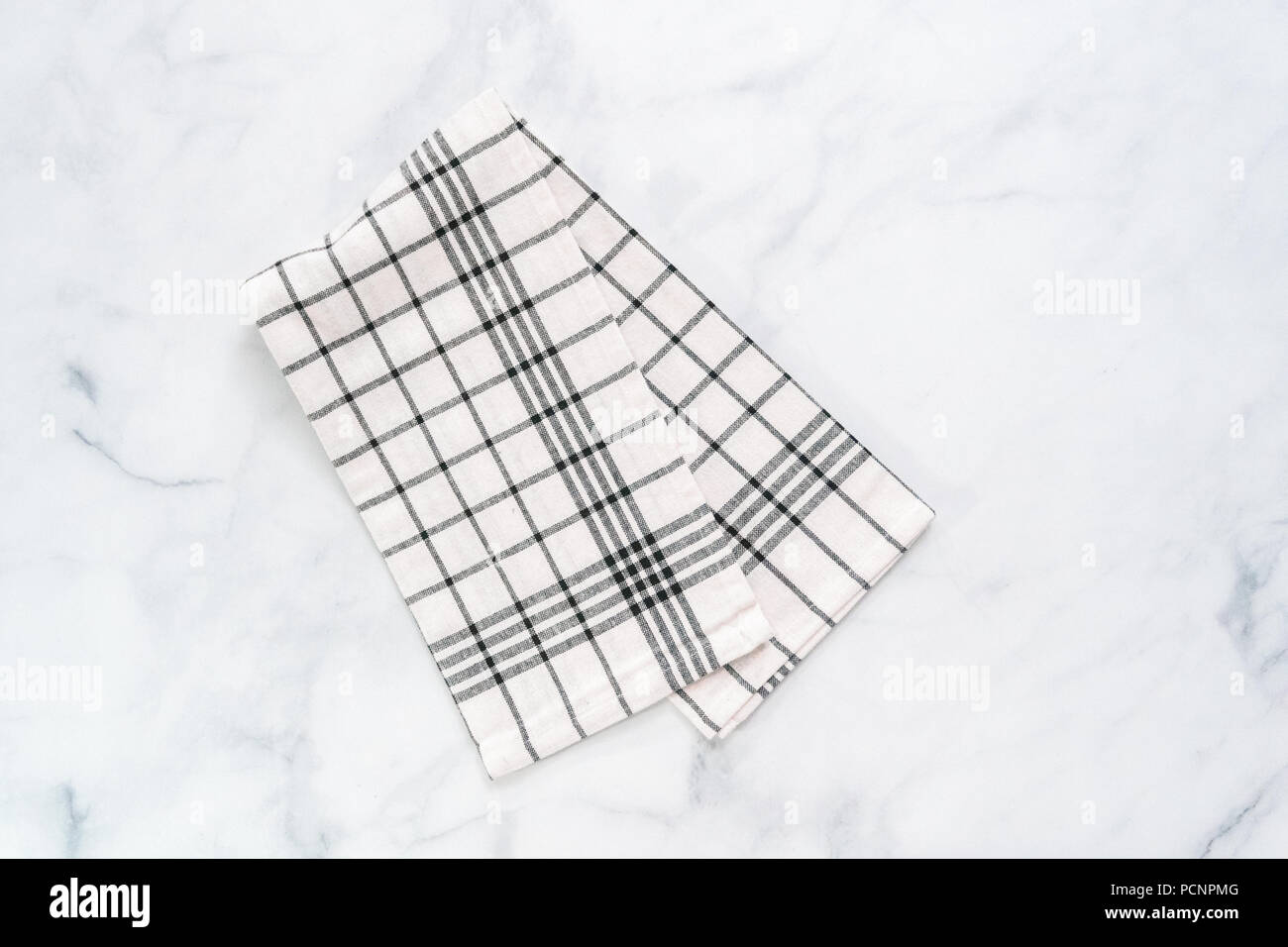 New kitchen towels with simple black pattern folded on marble counter ...
