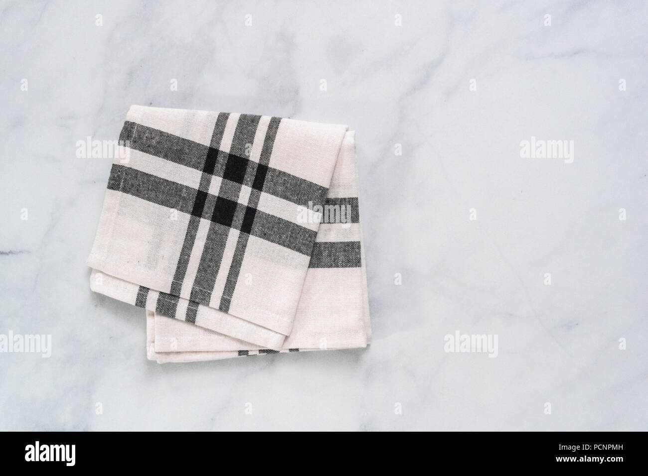 New kitchen towels with simple black pattern folded on marble counter ...