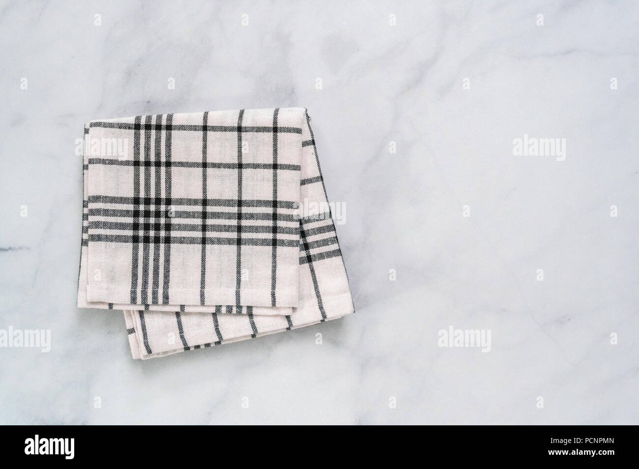 New kitchen towels with simple black pattern folded on marble counter ...
