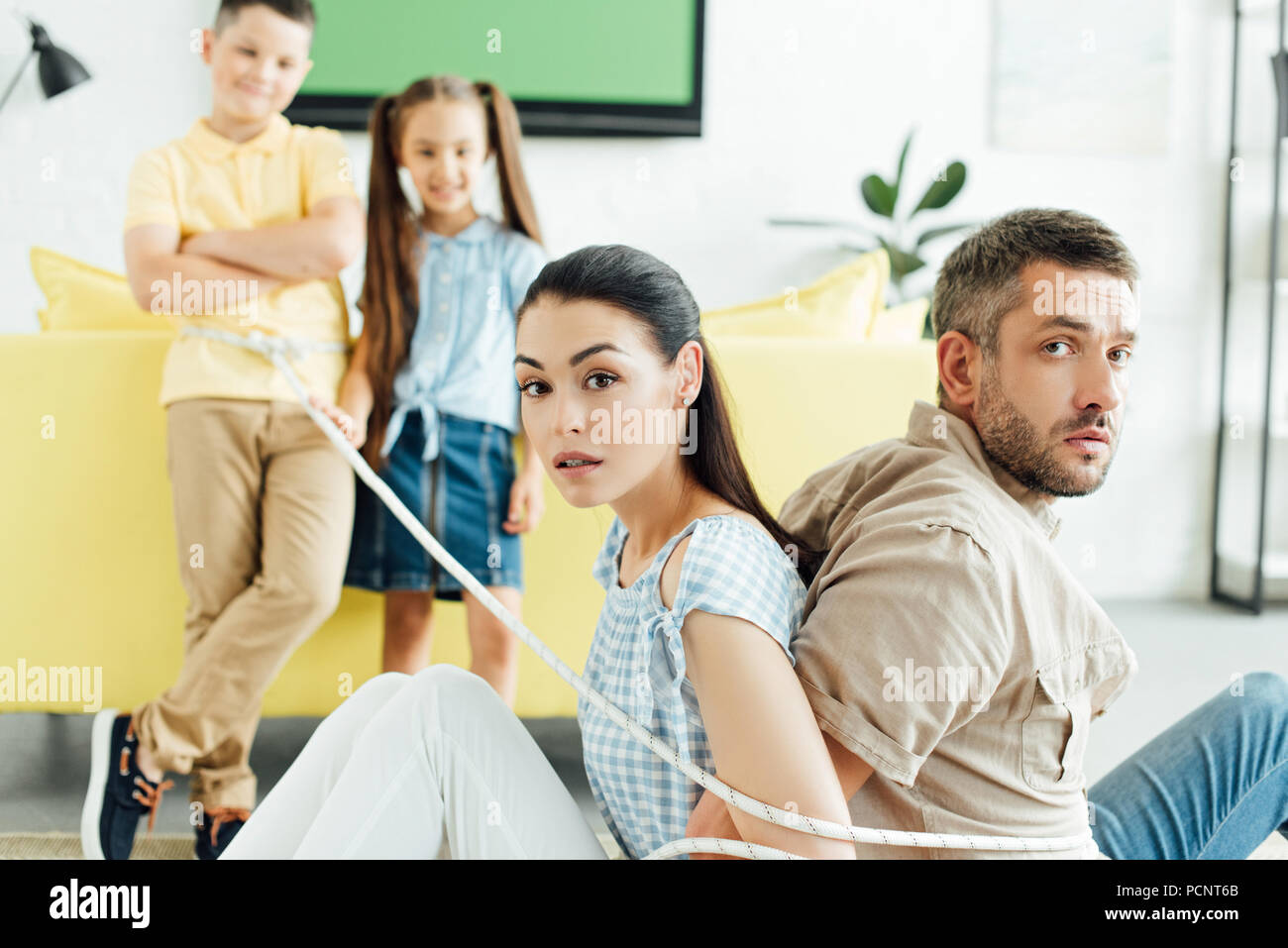 children tying scared parents with rope on floor at home Stock Photo ...