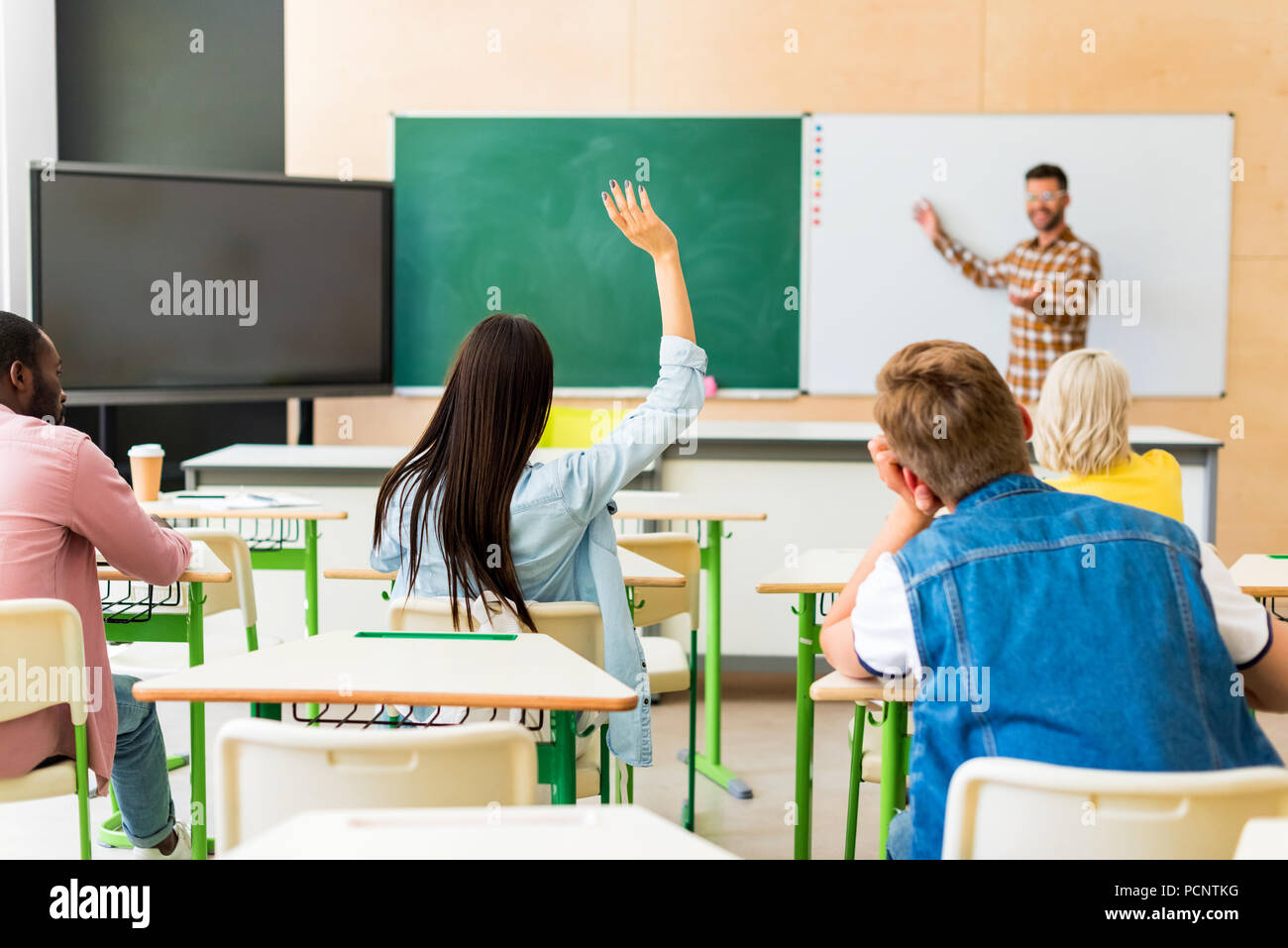 rear view of young students listening to teachers lecture at college ...
