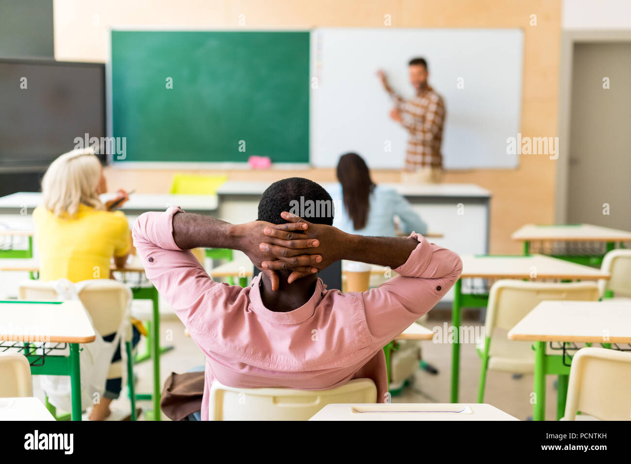 back view of relaxed african american student sitting at classroom ...