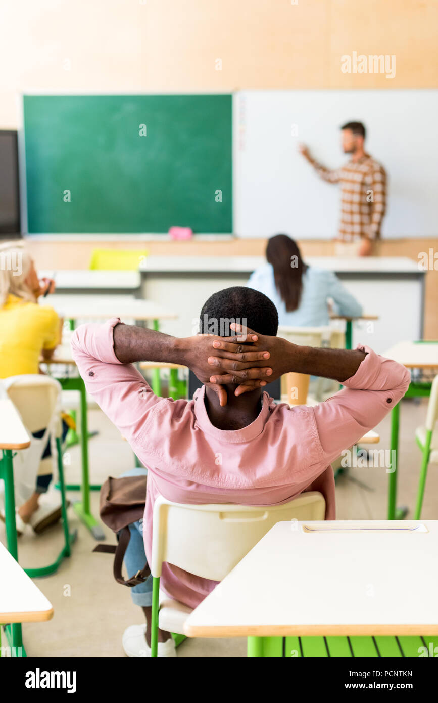 rear view of relaxed african american student sitting at classroom ...