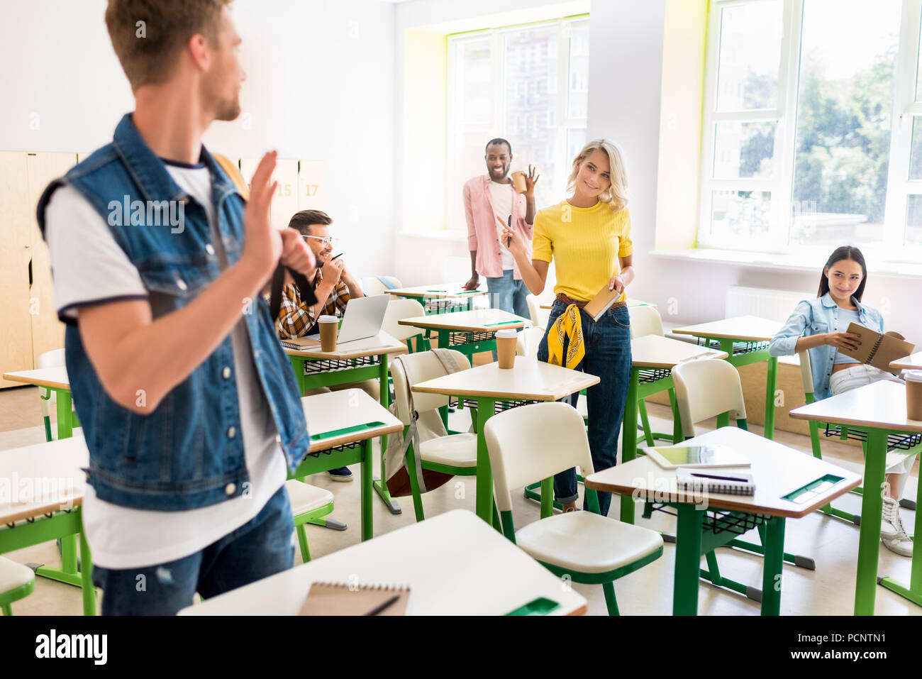 young students greeting each other in classroom Stock Photo - Alamy