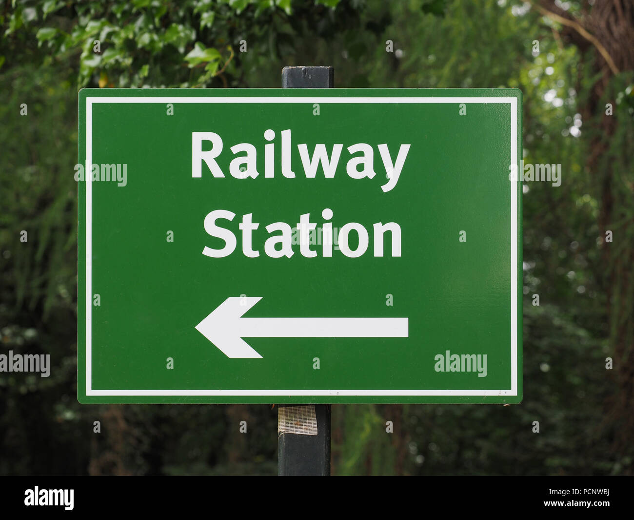 Railway station direction sign, white over green Stock Photo - Alamy