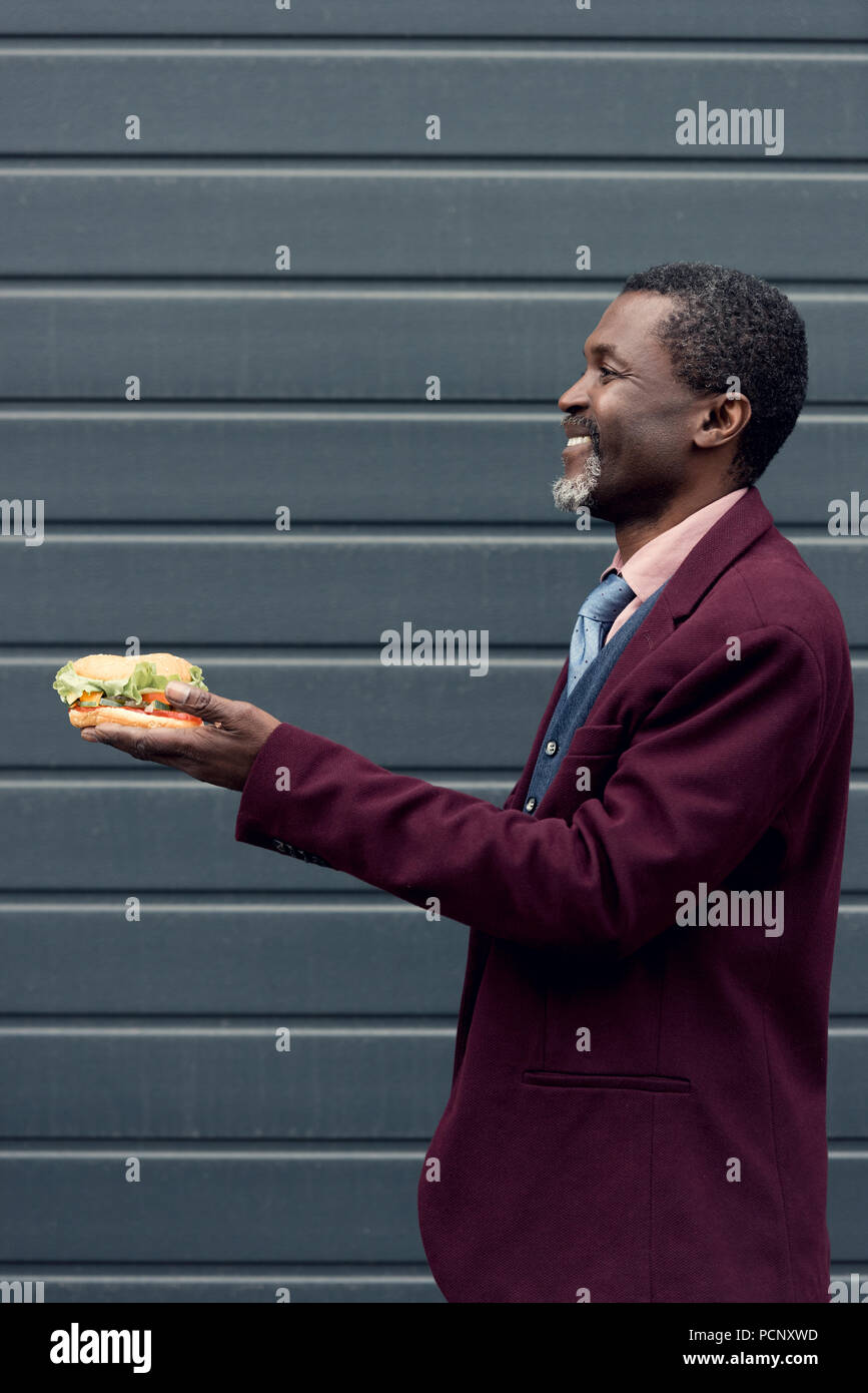 fashionable smiling african american man holding burger Stock Photo - Alamy