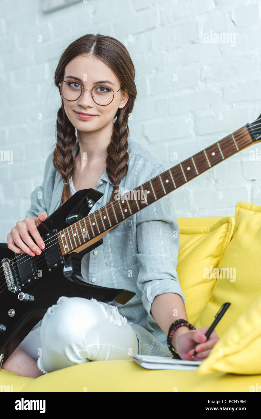 beautiful teen girl with electric guitar writing song in textbook Stock ...