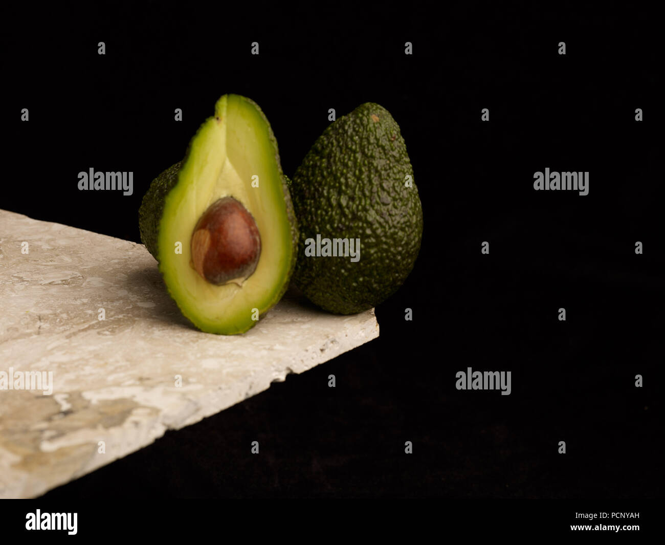 Avocado on tile on black background Stock Photo - Alamy