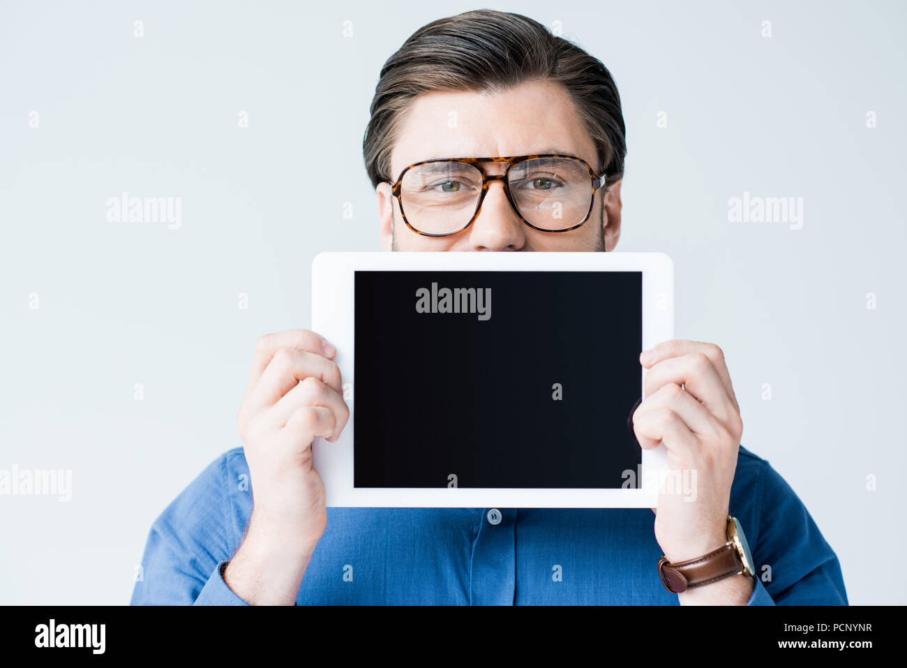 young man covering half of face with tablet with blank screen isolated ...