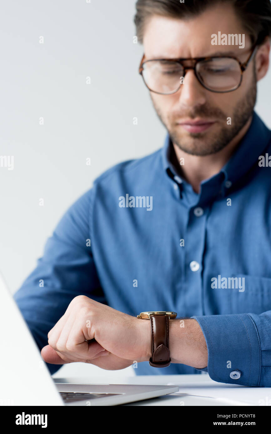 handsome young businessman looking at watch during work isolated on ...