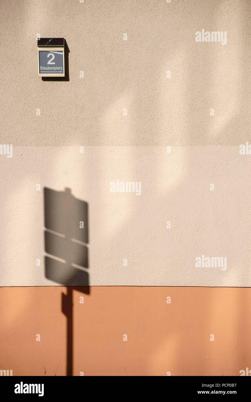 A road sign throwing an abstract shadow on a house wall with a house ...