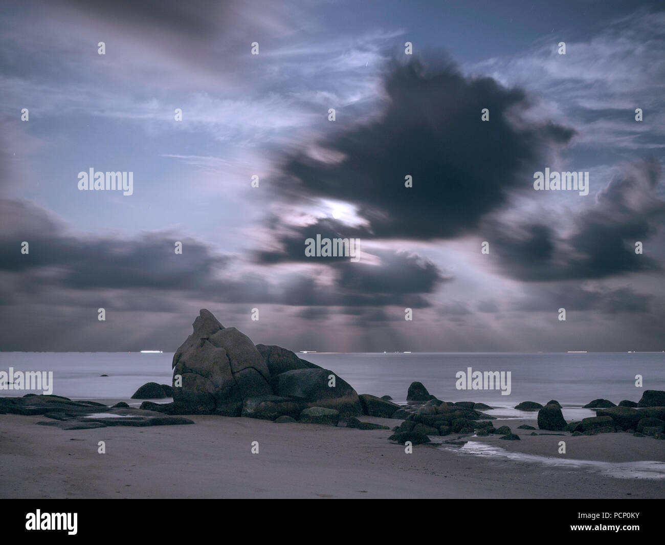 The full moon makes the sea shimmer silky and brightens the rocky beach ...