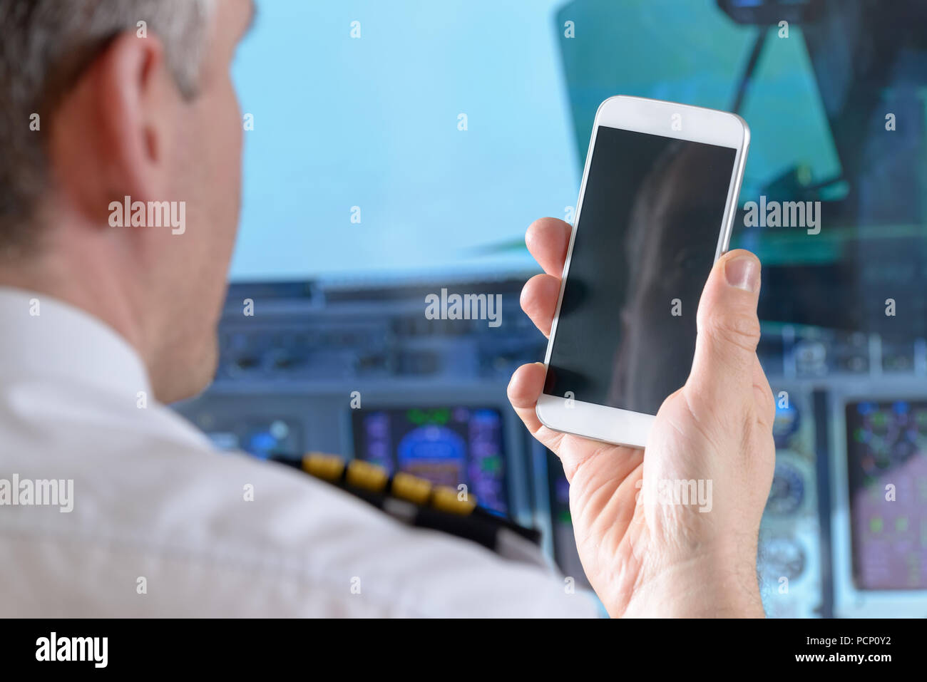 Airline pilot wearing uniform with epauletes using smart phone in ...