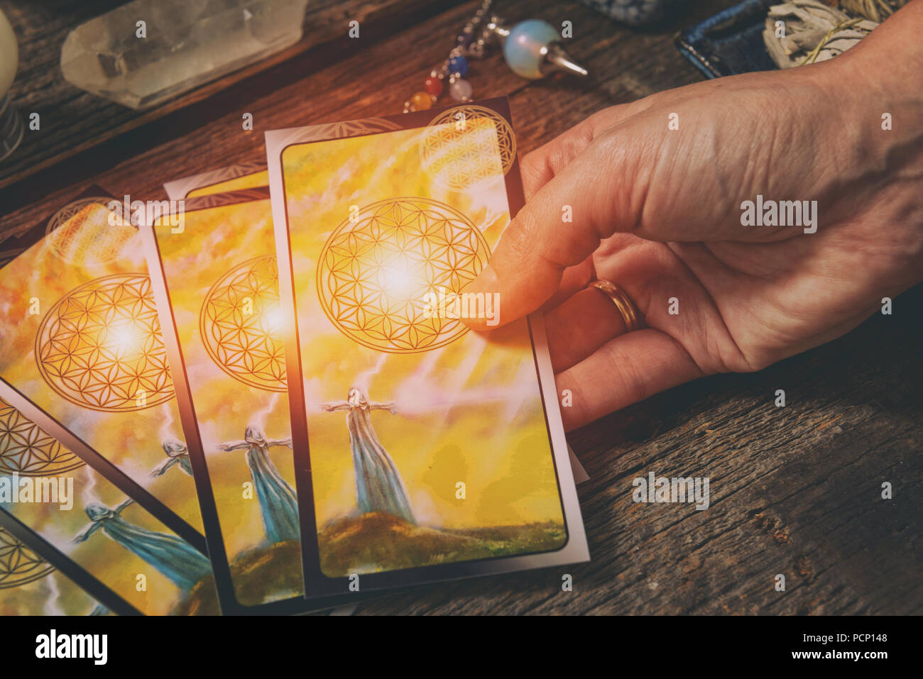 Tarot cards in hand, dowsing tool and crystals on a wooden board Stock ...