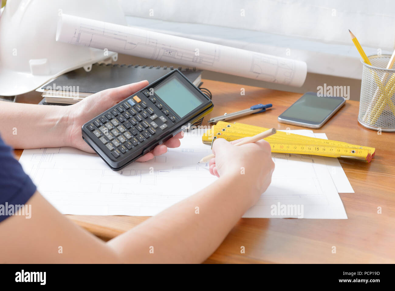 Architect using engineering calculator at his work. Construction plans ...