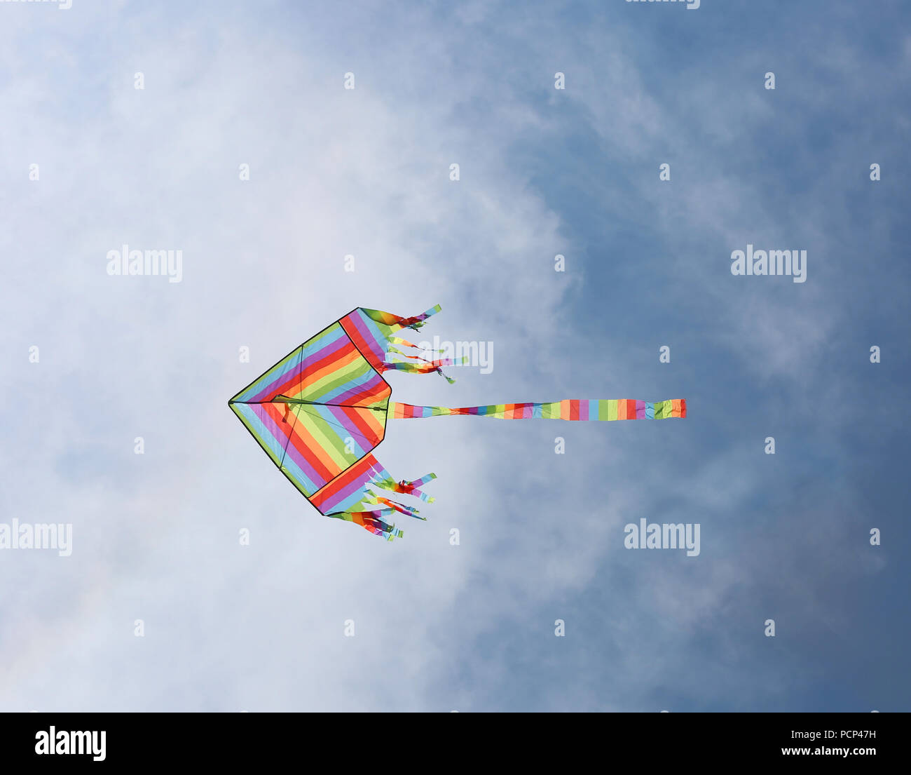 kite with the colors of the rainbow flies high in the blue sky Stock ...