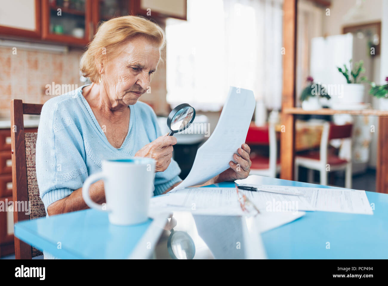 Elderly woman looking at her utility bills and paperwork Stock Photo ...