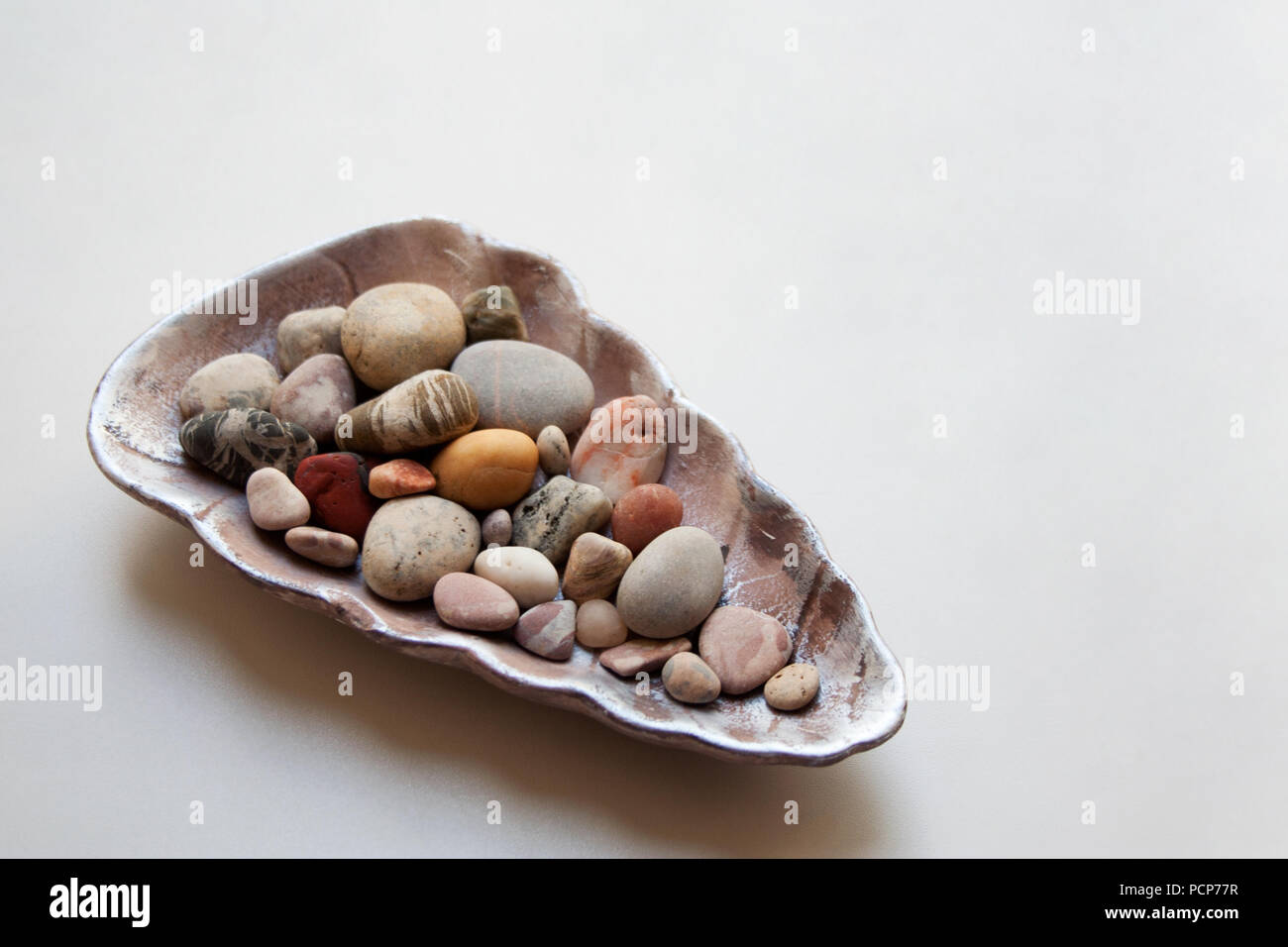 Sea stones colored in various patterns inside a glossy seashell ...