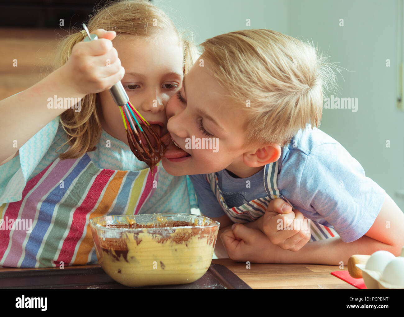 Two happy children having fun and taste chocolate dough in the modern ...