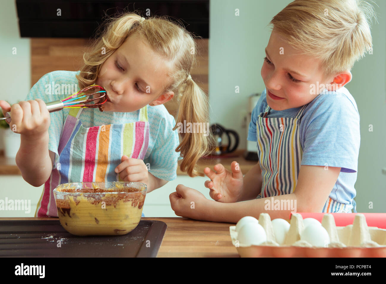 Two happy children having fun and taste chocolate dough in the modern ...