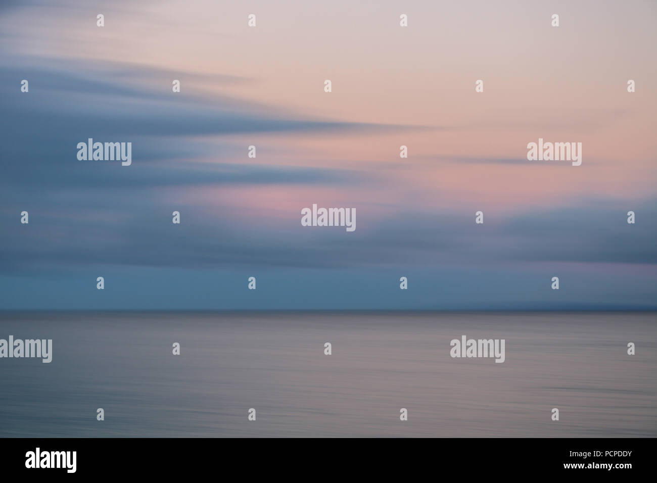 Muted blur sunrise over ocean with pink and gray clouds Stock Photo - Alamy
