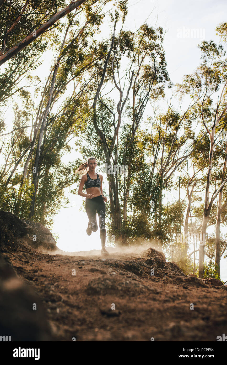 sporty woman running on country trail. Female athlete running through ...