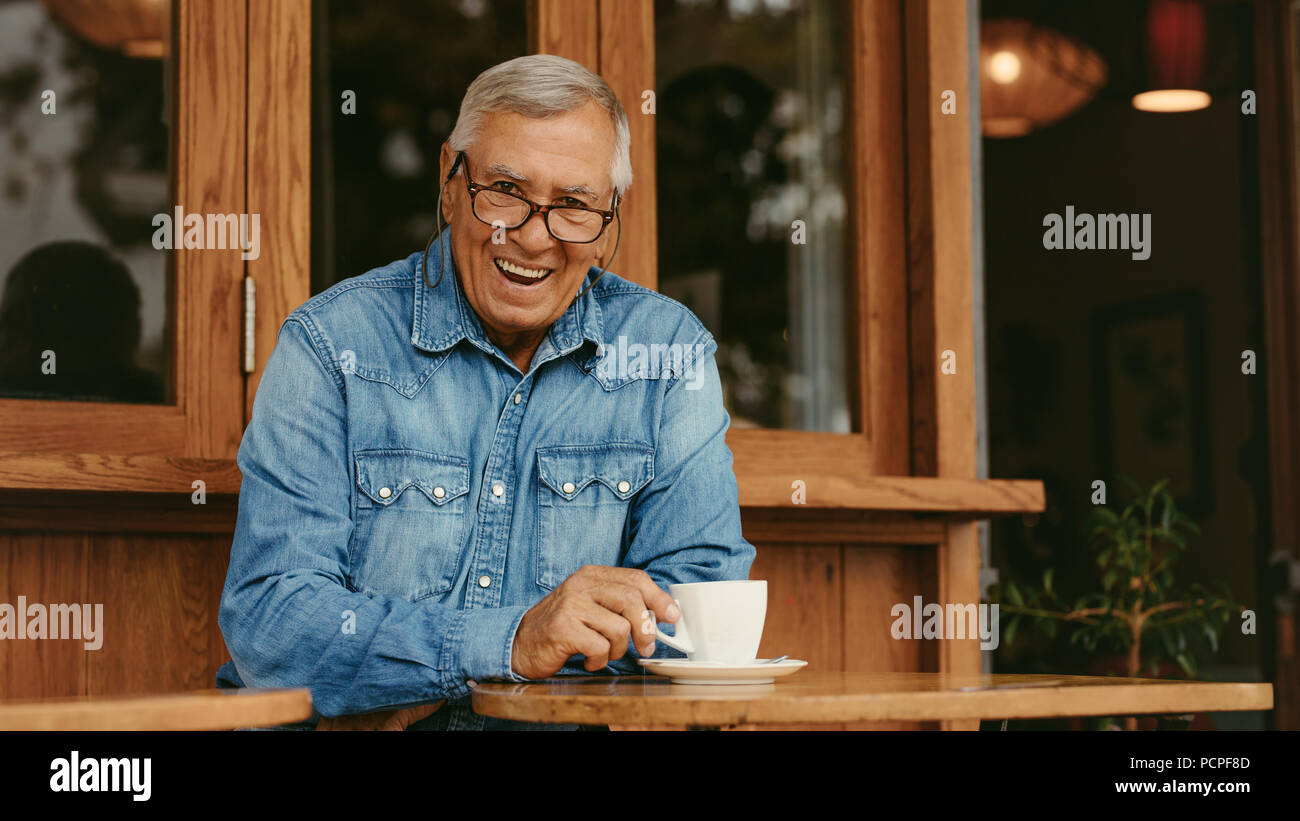 Portrait of happy retired man having coffee at coffeeshop. Smiling ...