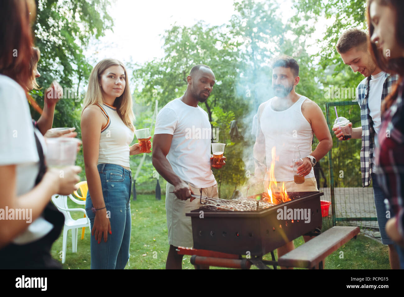 Group of friends making barbecue in the backyard. concept about good ...