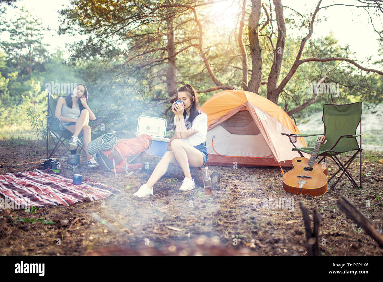 Party, camping of women at forest. They relaxing, singing a song and ...