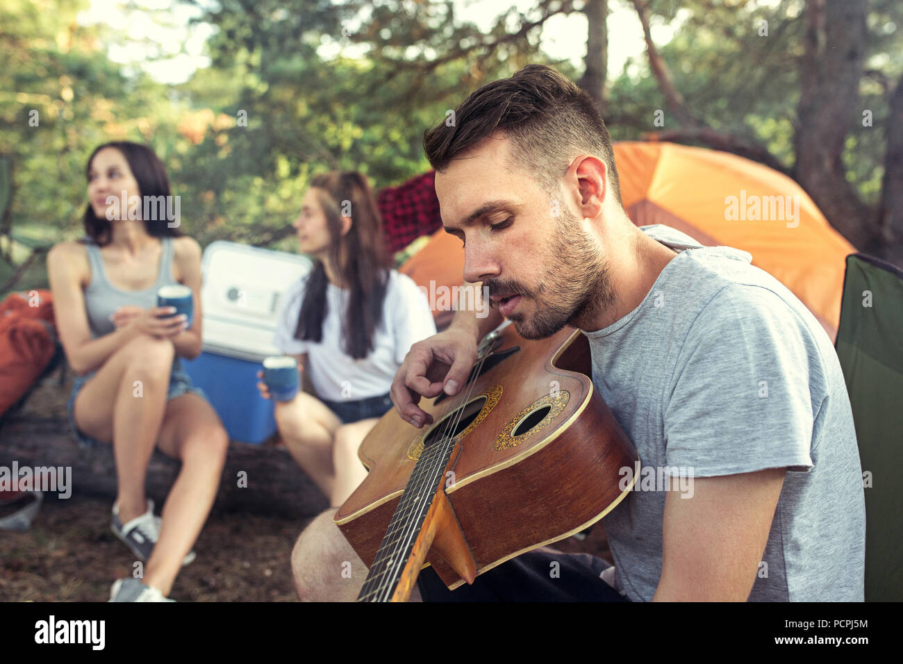 Party, camping of men and women group at forest. They relaxing, singing ...