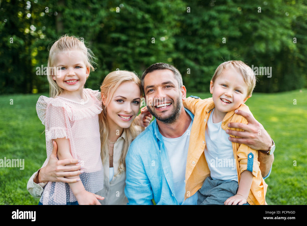 happy family with two kids smiling at camera together in park Stock ...