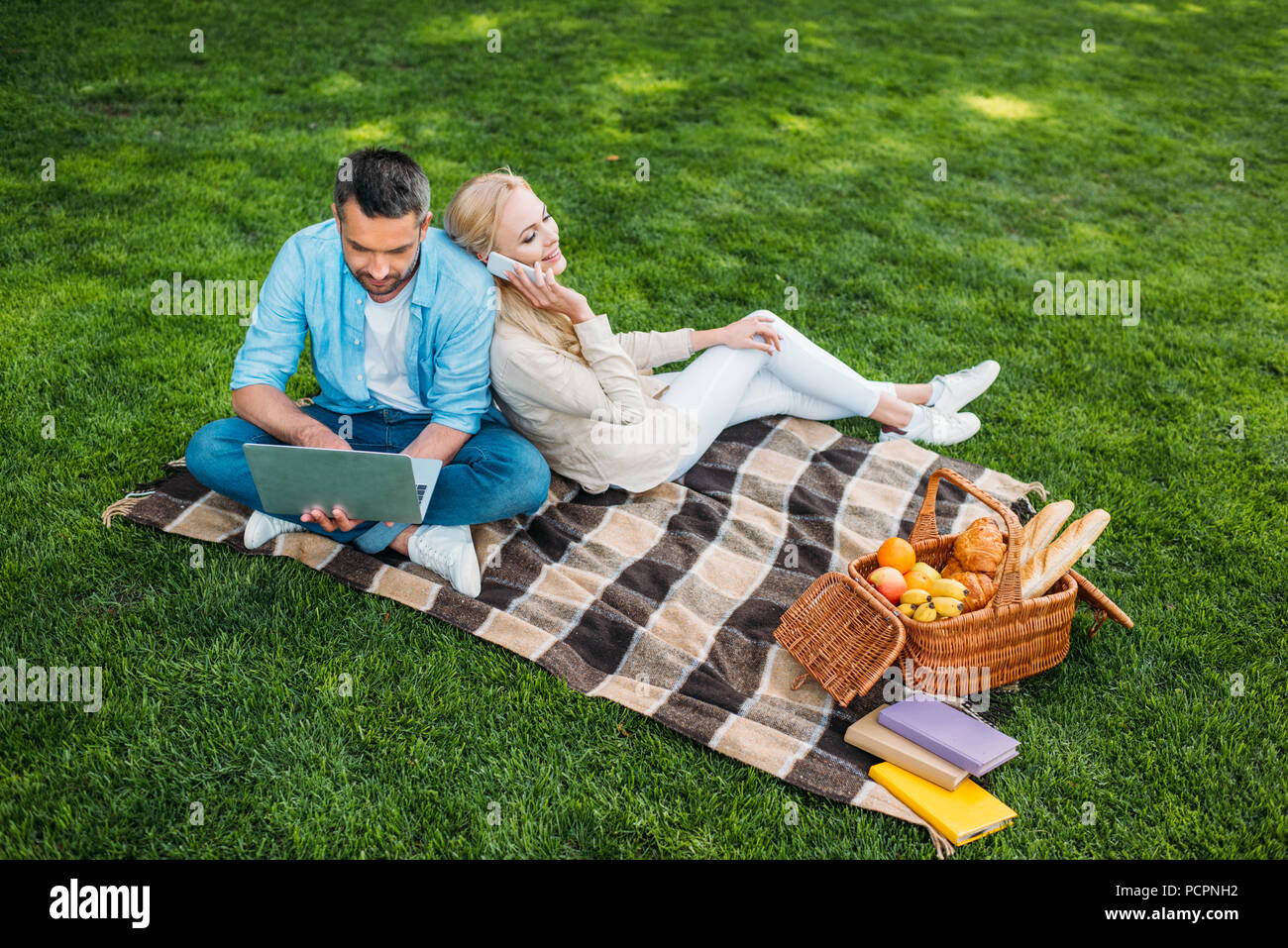 high angle view of happy couple using smartphone and laptop while ...