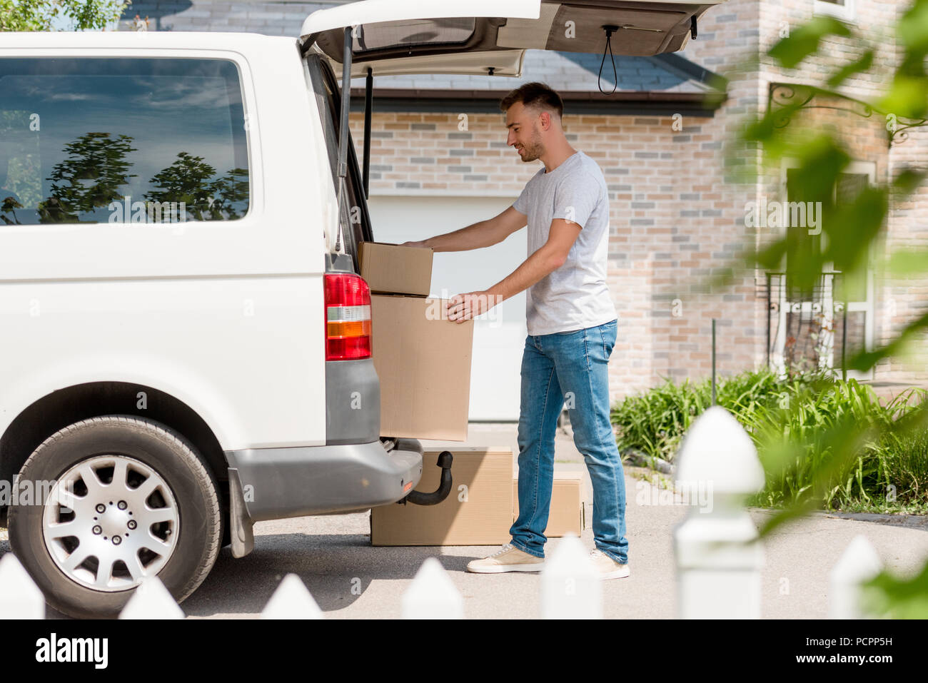 side view of young man moving boxes from car into new house Stock Photo ...