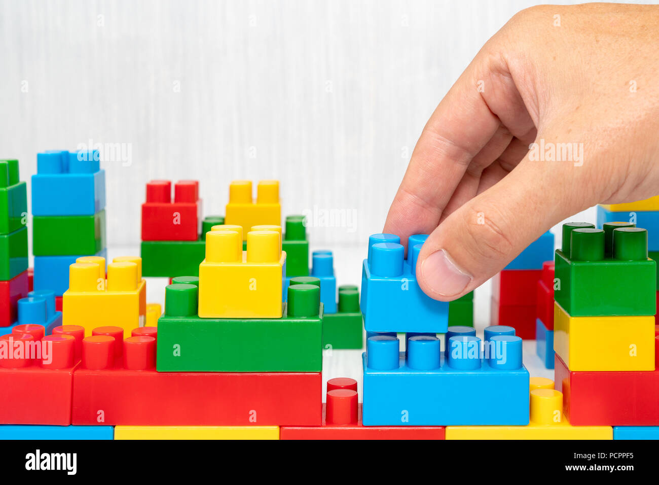 Hand building up a wall by stacking up block Stock Photo - Alamy