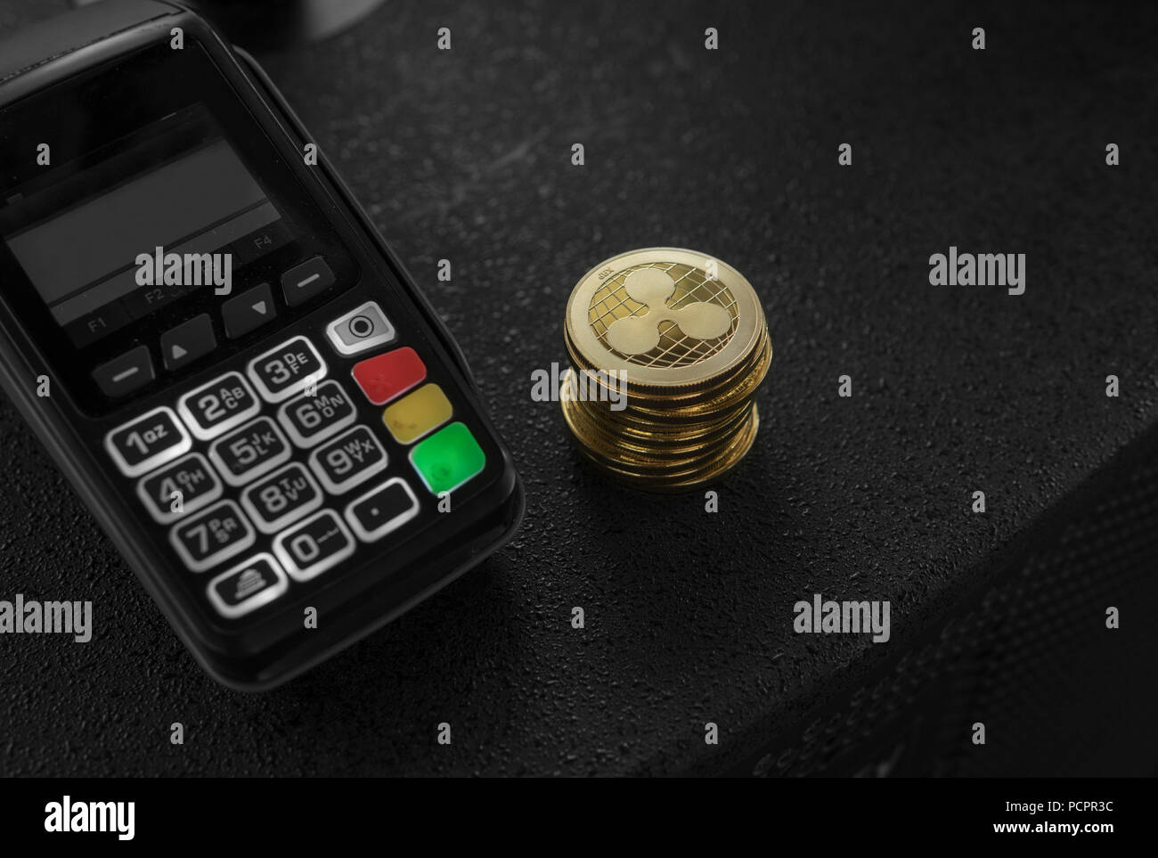 A pile of gold Ripple Crypto currency coins and POS terminal. Ripples ...