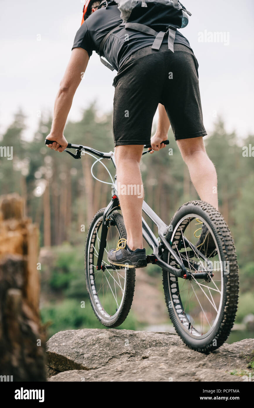 rear view of trial biker balancing on cliff outdoors Stock Photo - Alamy