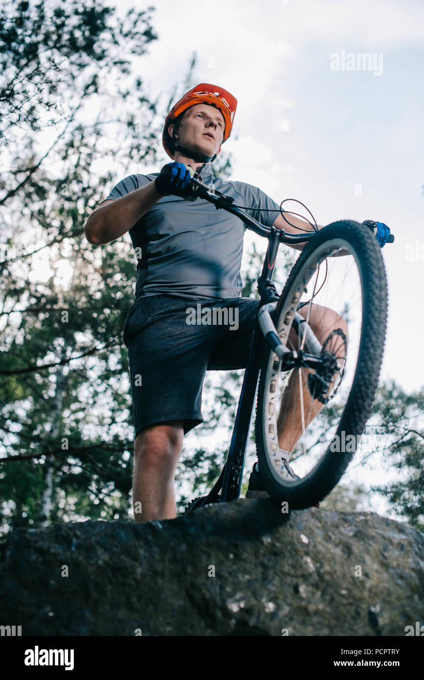 bottom view of handsome trial biker standing on rock outdoors Stock ...