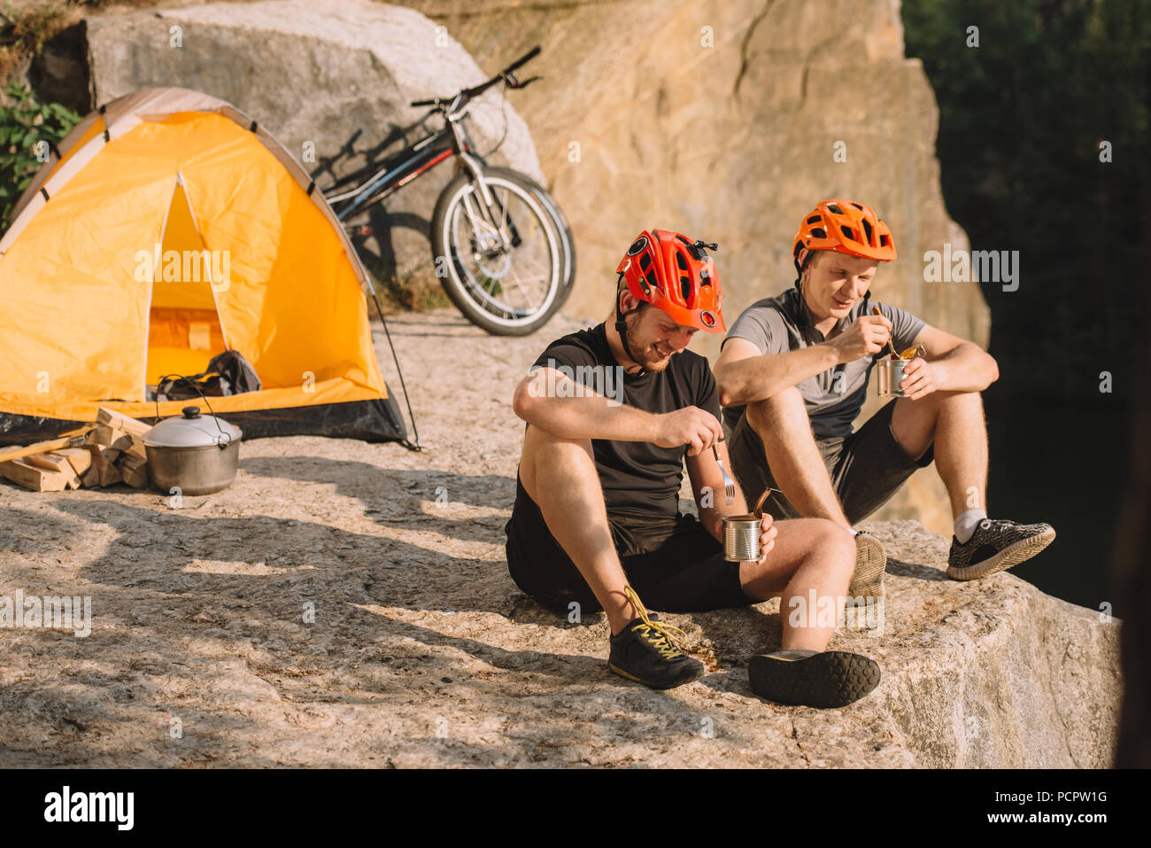 happy trial bikers eating canned food in camping on cliff Stock Photo ...