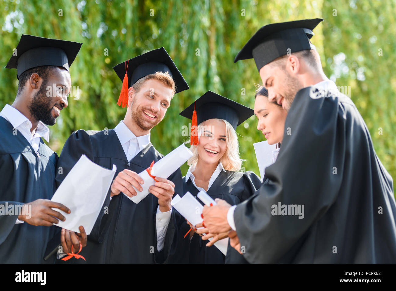happy young graduated students in capes with diplomas Stock Photo - Alamy