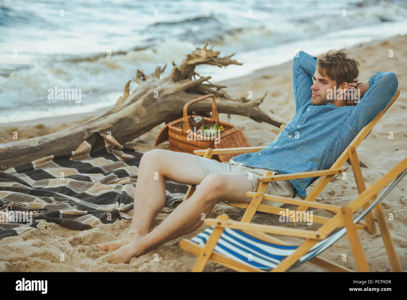 side view of young man resting in beach chair on sandy beach Stock ...