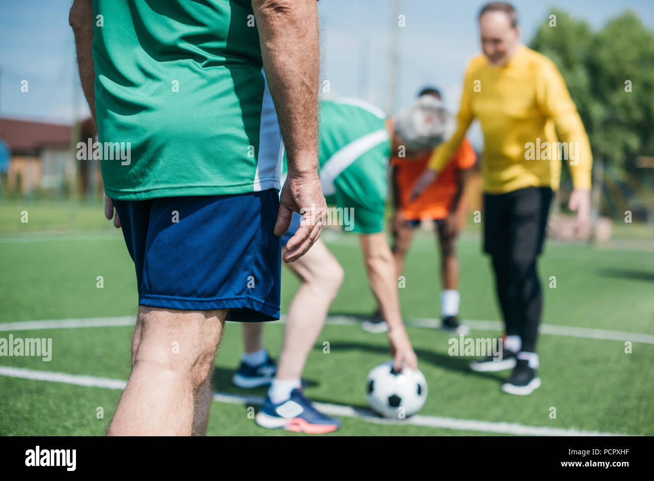 partial view of multicultural elderly friends playing football together ...