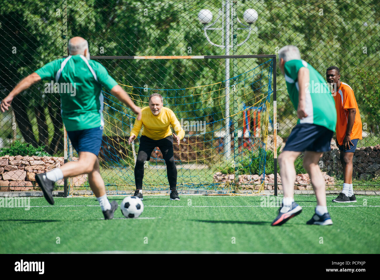 selective focus of multicultural elderly friends playing football ...