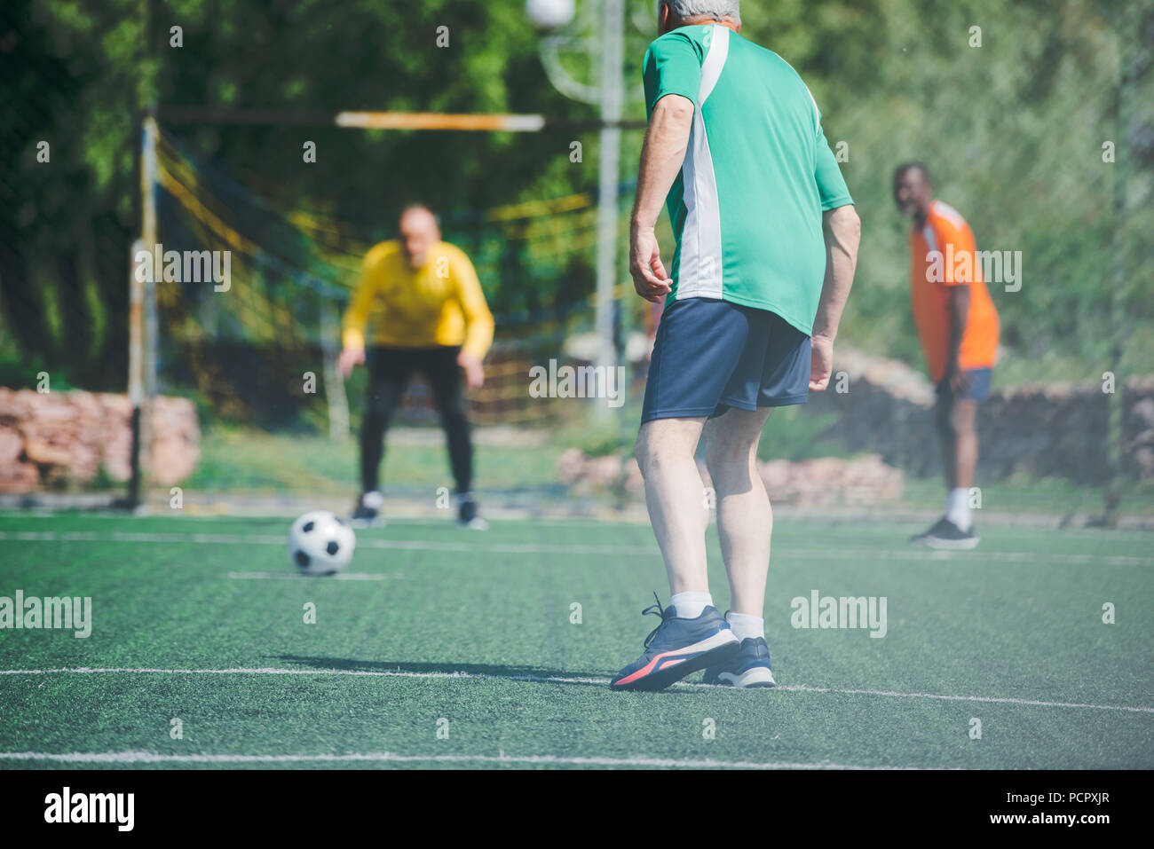 multiracial old men playing football together on green field Stock ...