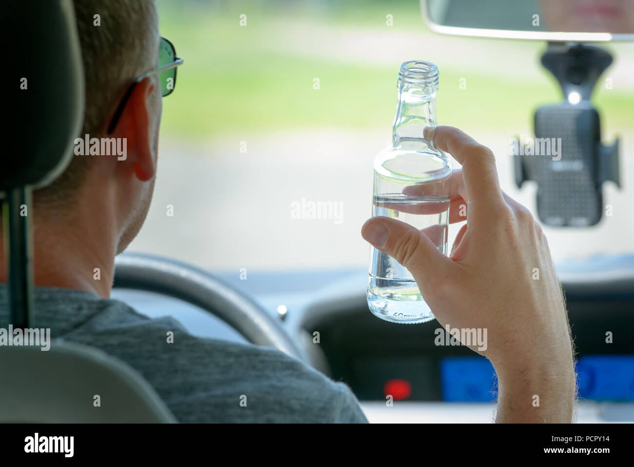 Man driving a car with a bottle of alcohol drink. Don't drink and drive ...